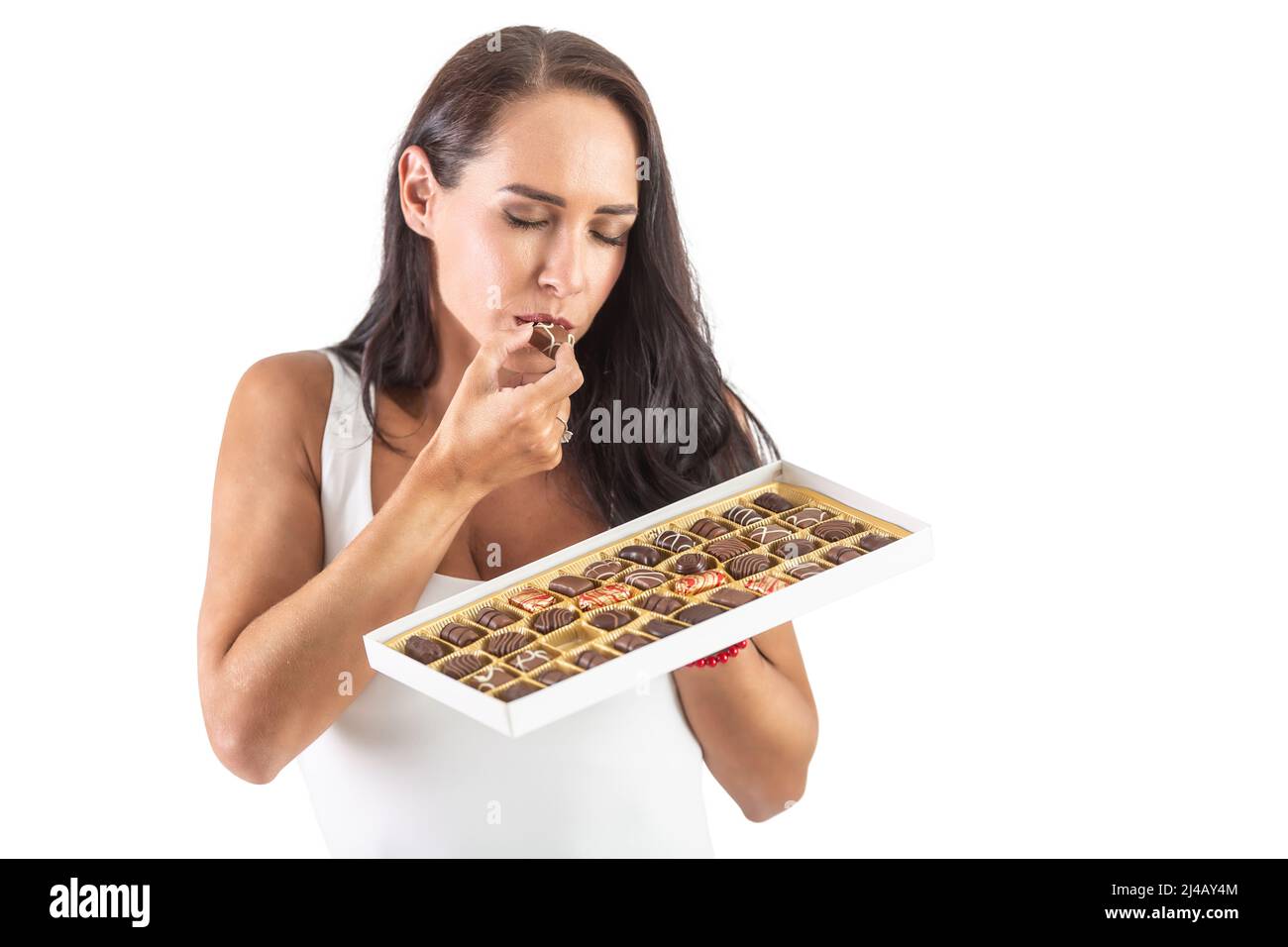 Attractive Dark Haired Woman Is Eating A Chocolate Candy While Holding