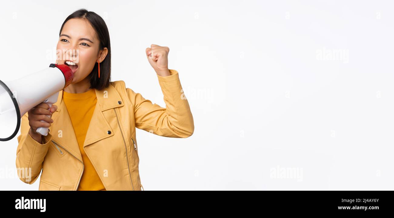 Portrait of young asian woman protester, screaming in megaphone and ...