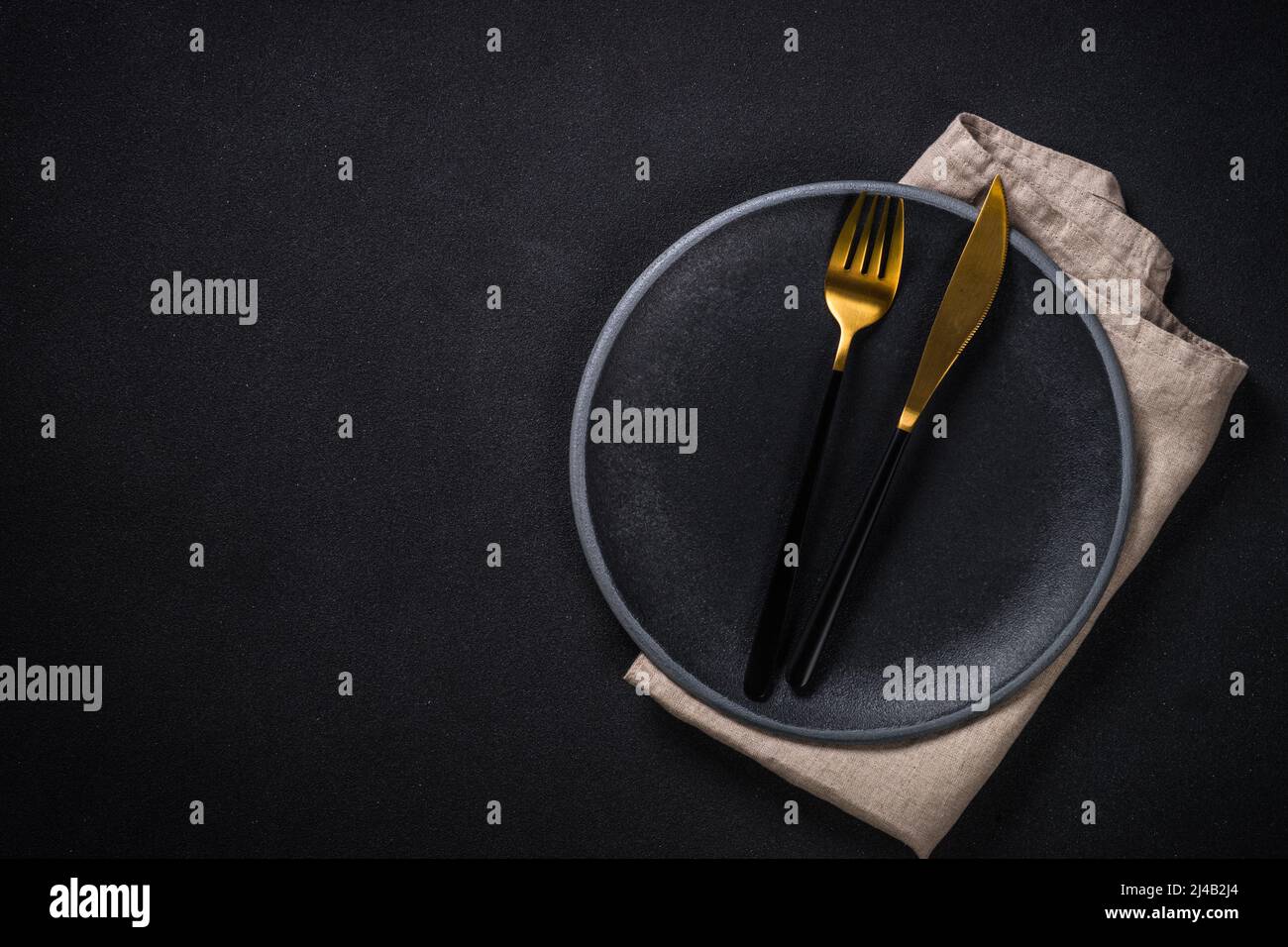 Table setting with black plate at black background Stock Photo - Alamy