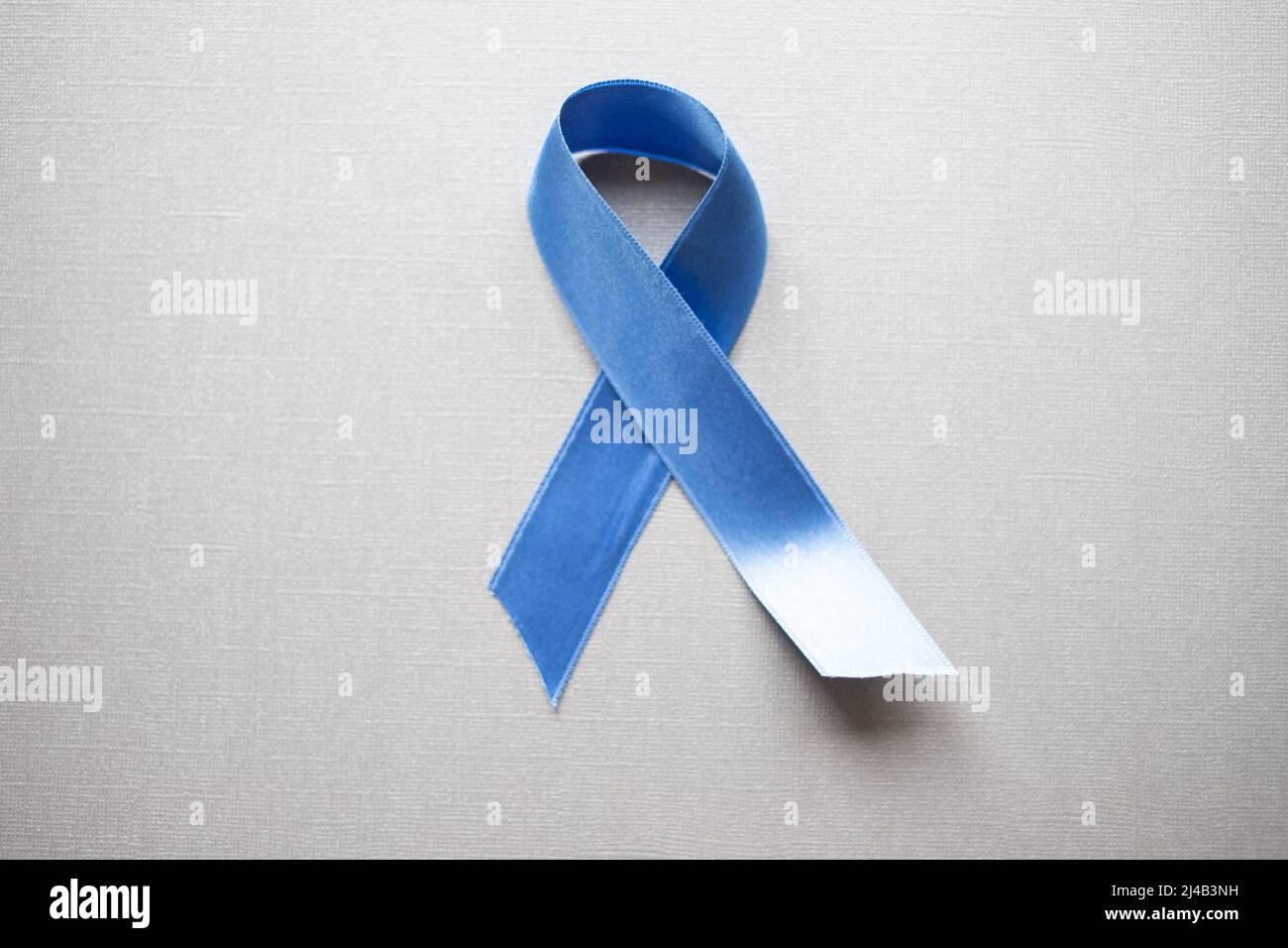 blue ribbon in hand prostate cancer awareness Stock Photo - Alamy