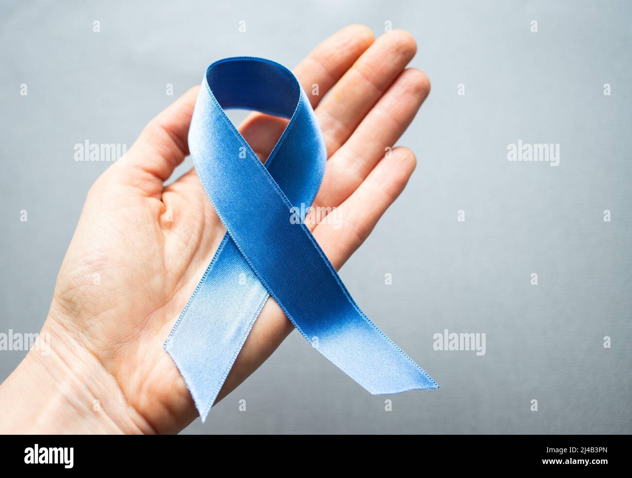 blue ribbon in hand prostate cancer awareness Stock Photo - Alamy
