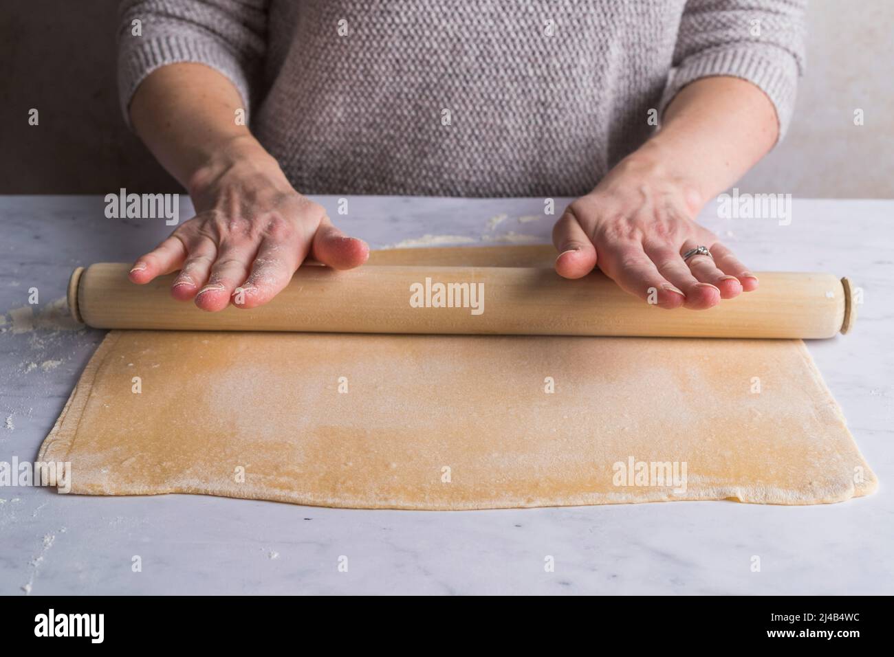 Fresh pasta being rolled with a rolling pin on a marble worktop Stock ...