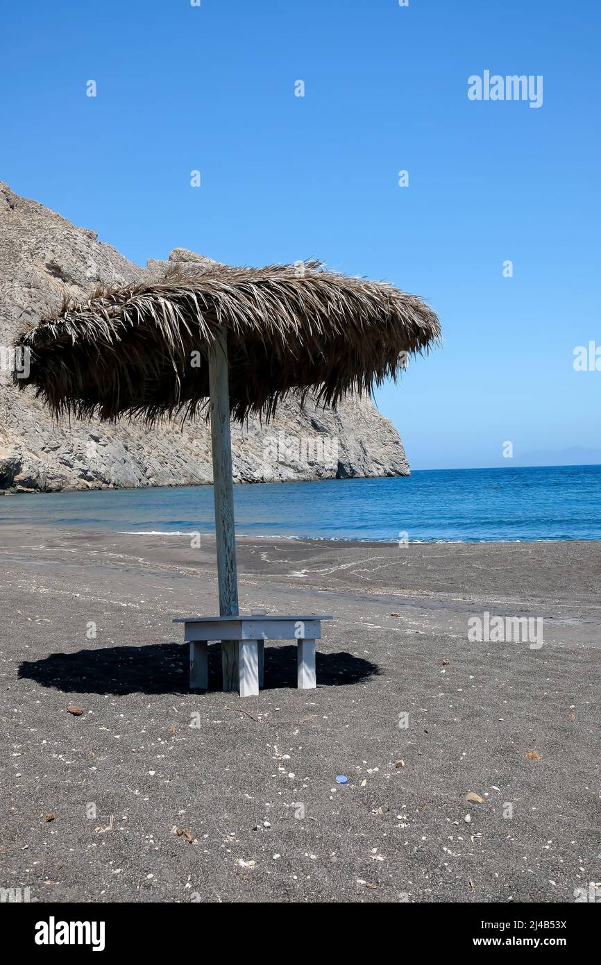A sun umbrella at the famous sandy black beach of Perissa Santorini ...