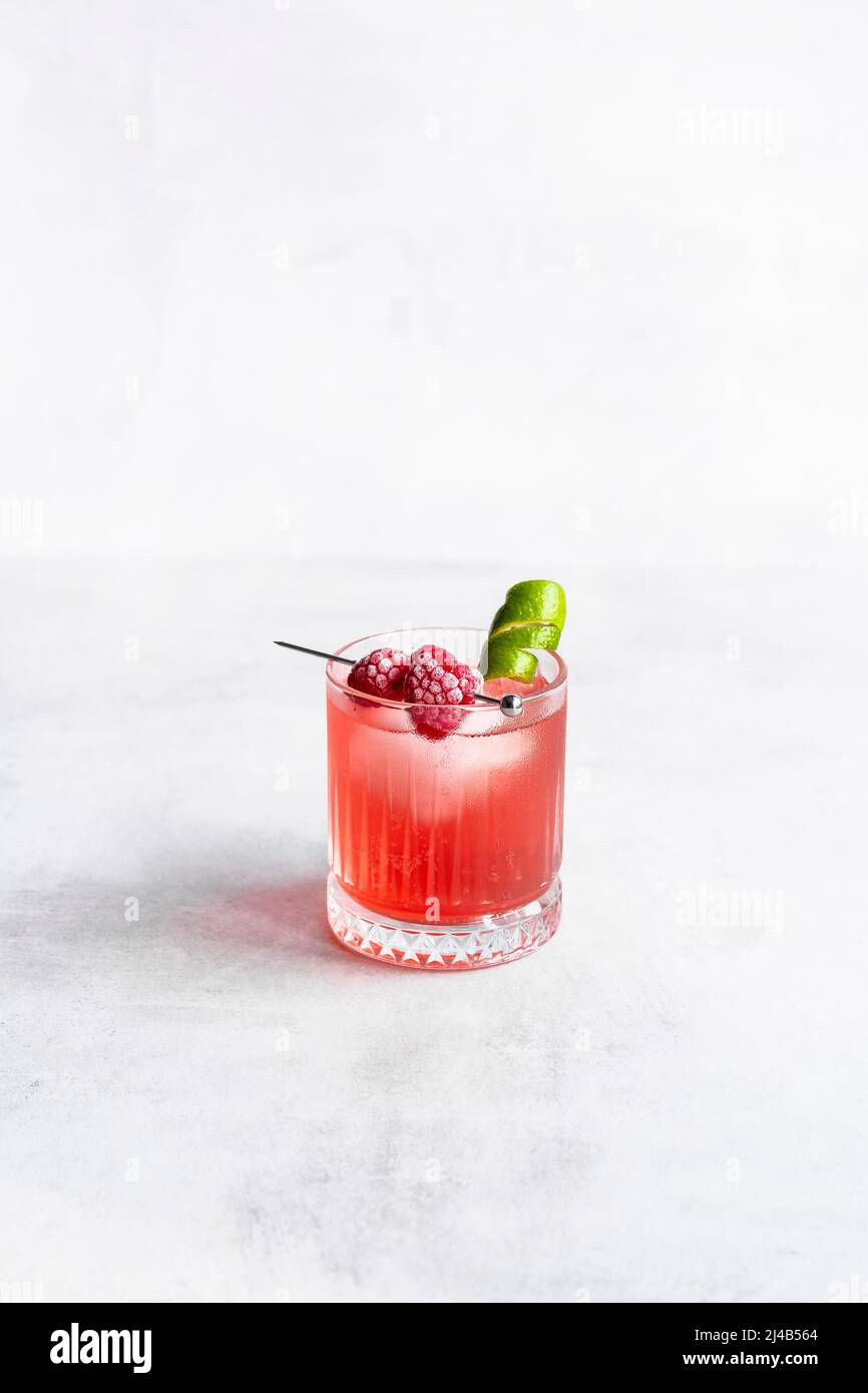 Raspberry and lime cocktail with frozen raspberries and lime garnish Stock Photo - Alamy