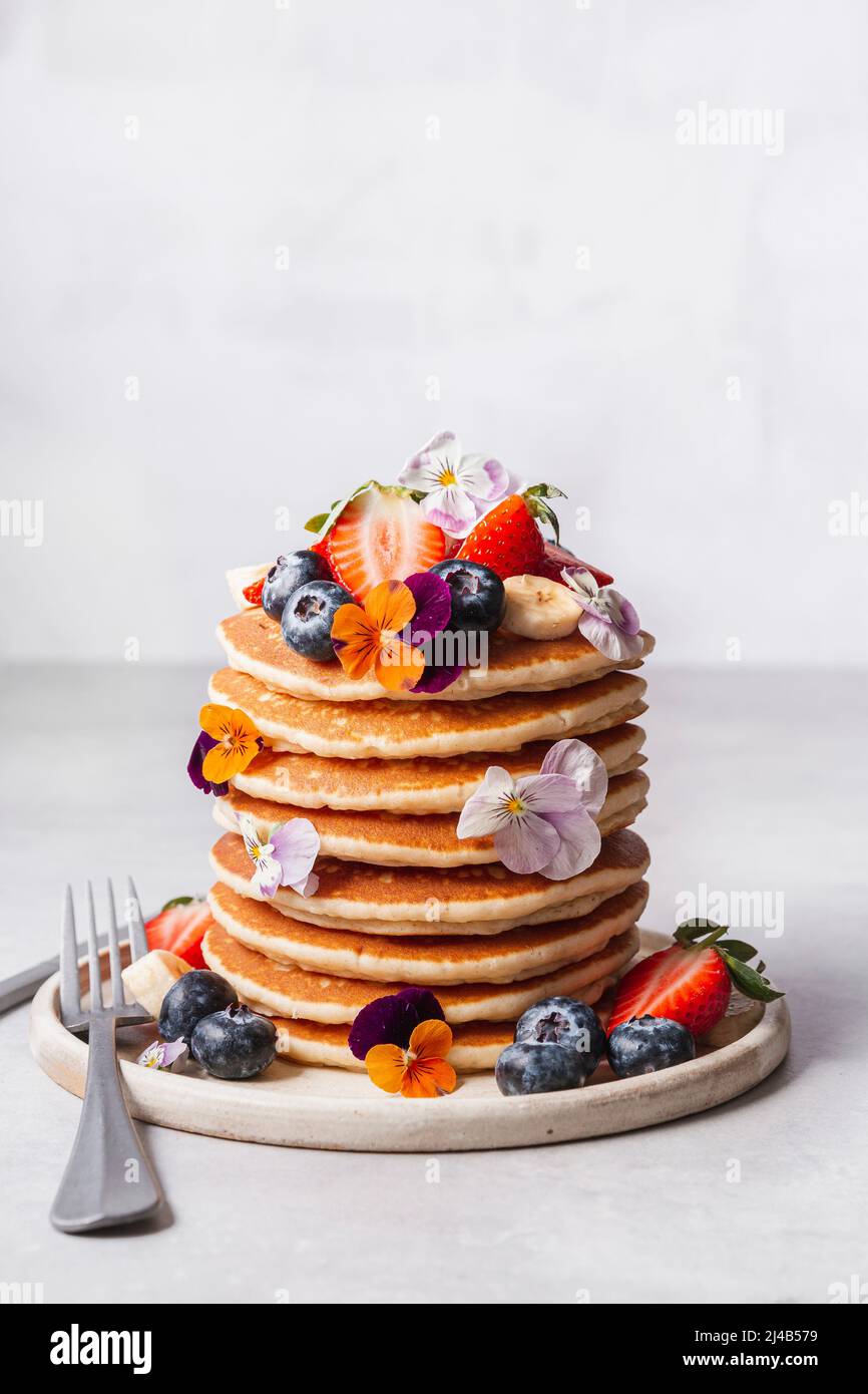 Pancake stack served with blueberries, strawberries, banana and edible ...