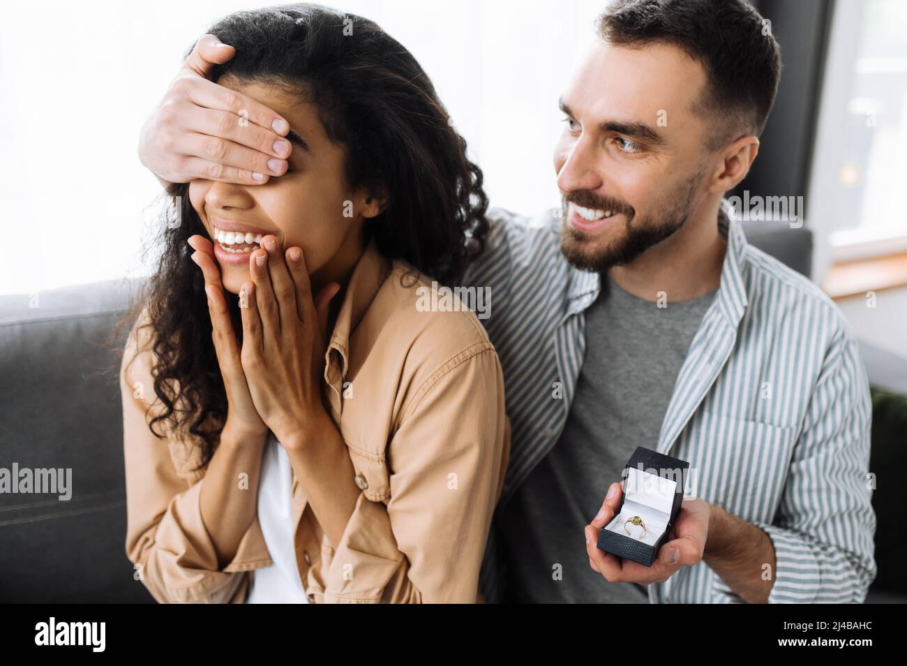 Multiracial couple in love at home on the living room sofa. The guy ...