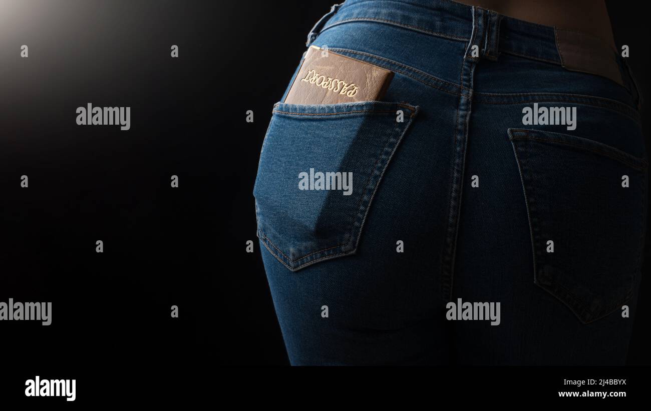 Passport in the back pocket of the girl's jeans. On a black background ...