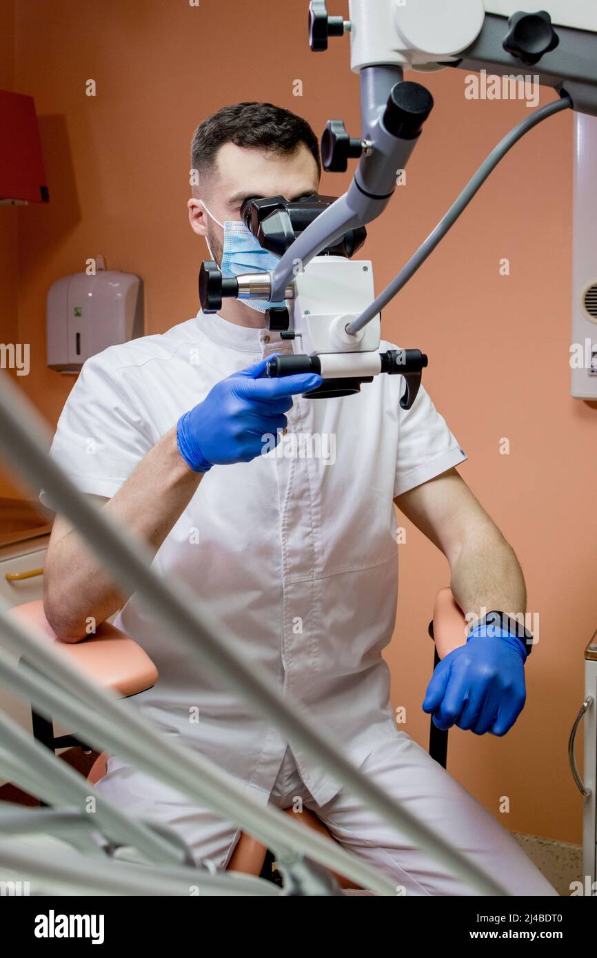 A male dentist looks into a microscope. Modern dentistry using new ...