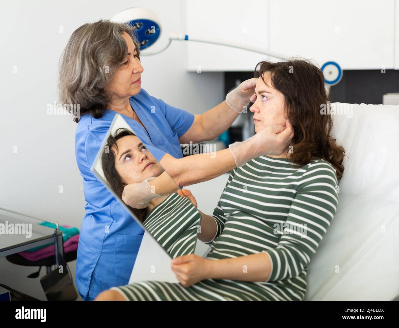 Experienced cosmetology doctor examines face a young woman patient ...