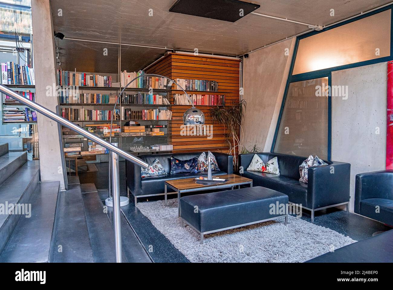 Comfortable sofa with pillows and bookshelves in library at hotel lobby ...