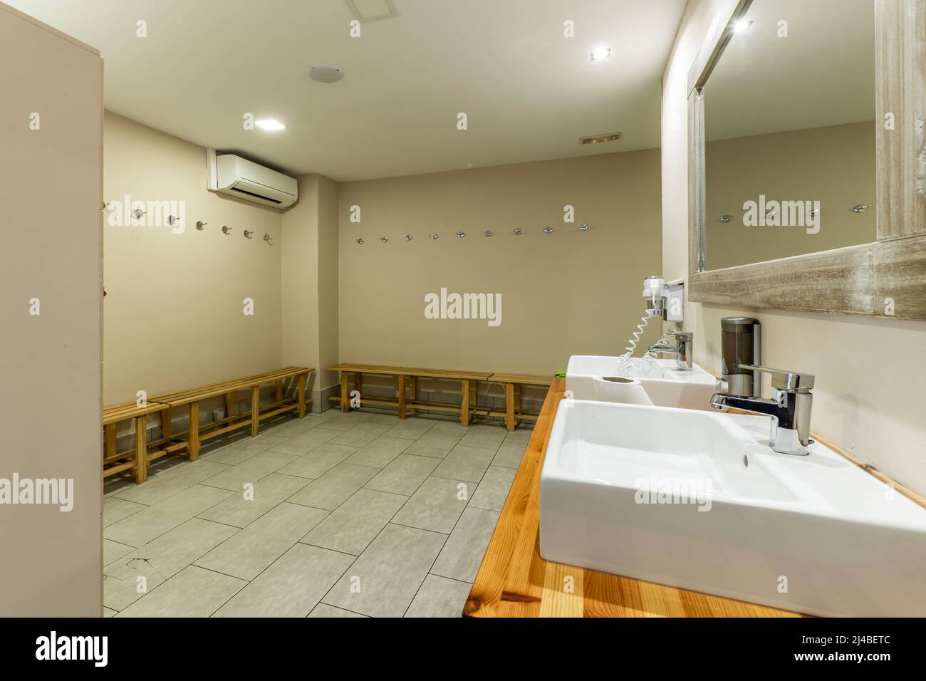 White porcelain sinks under a mirror in the common bathrooms of a gym ...