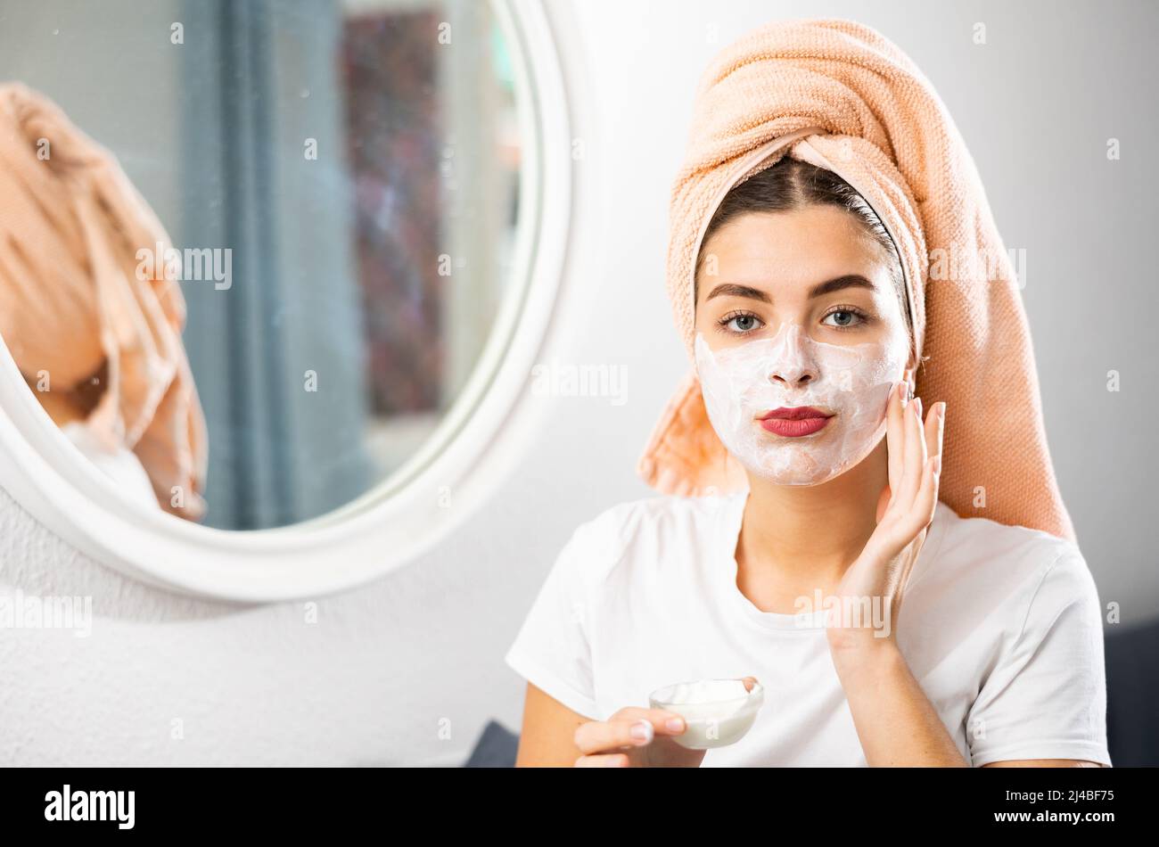 Happy woman taking care of face skin with lotion Stock Photo - Alamy
