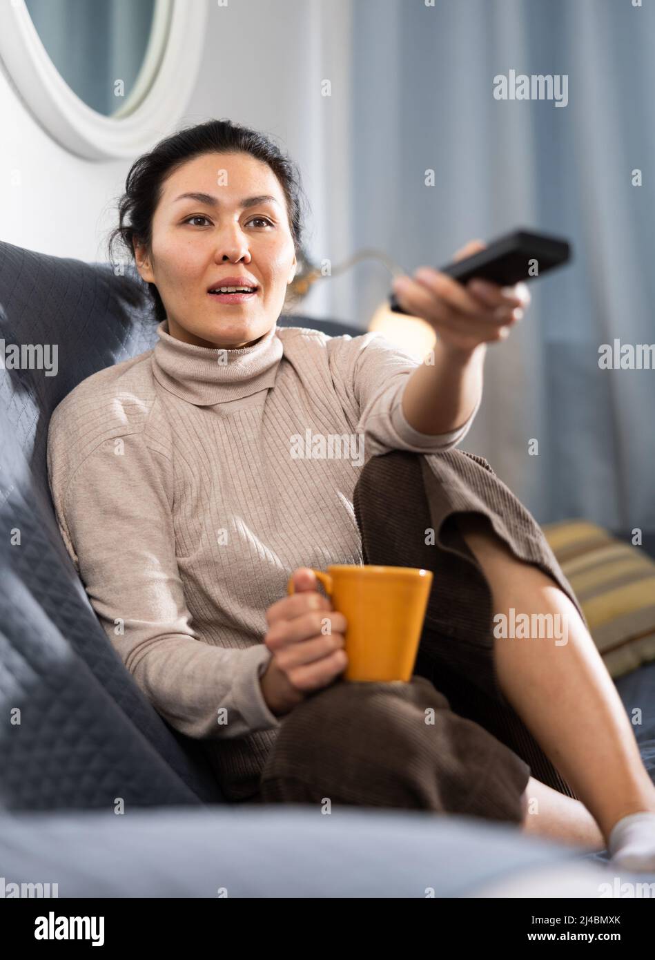 Asian woman watching TV Stock Photo - Alamy