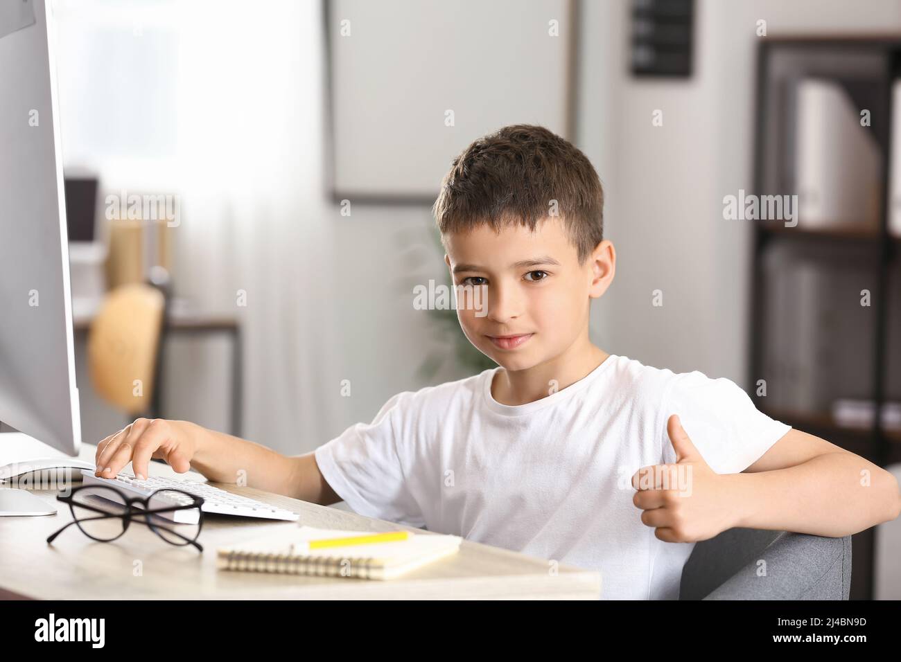 Cute little programmer showing thumb-up gesture during learning at home Stock Photo - Alamy