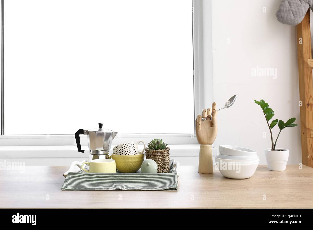 Tray with clean tableware, coffee pot and houseplant on counter in ...