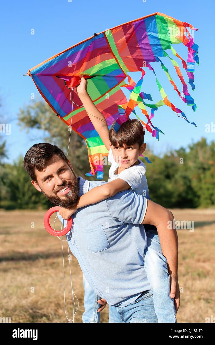 Happy father carrying pickaback his little son with kite in park Stock ...