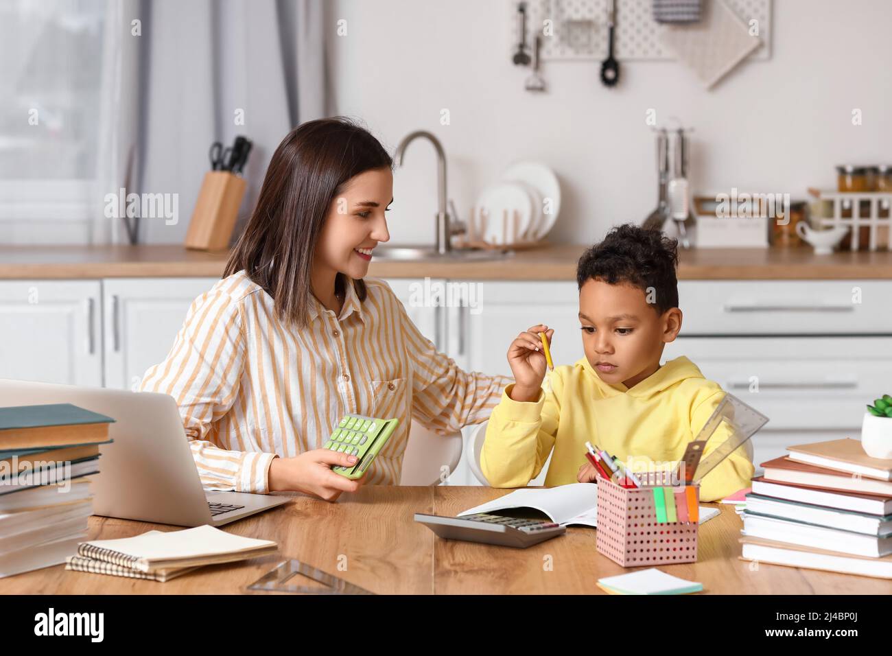 Little African-American boy studying Mathematics with tutor at home ...