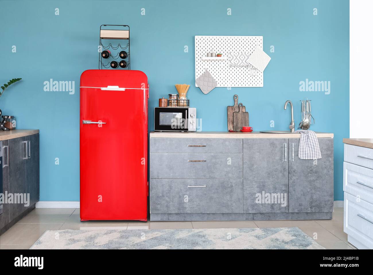 Interior of stylish kitchen with red fridge, counters and pegboard ...