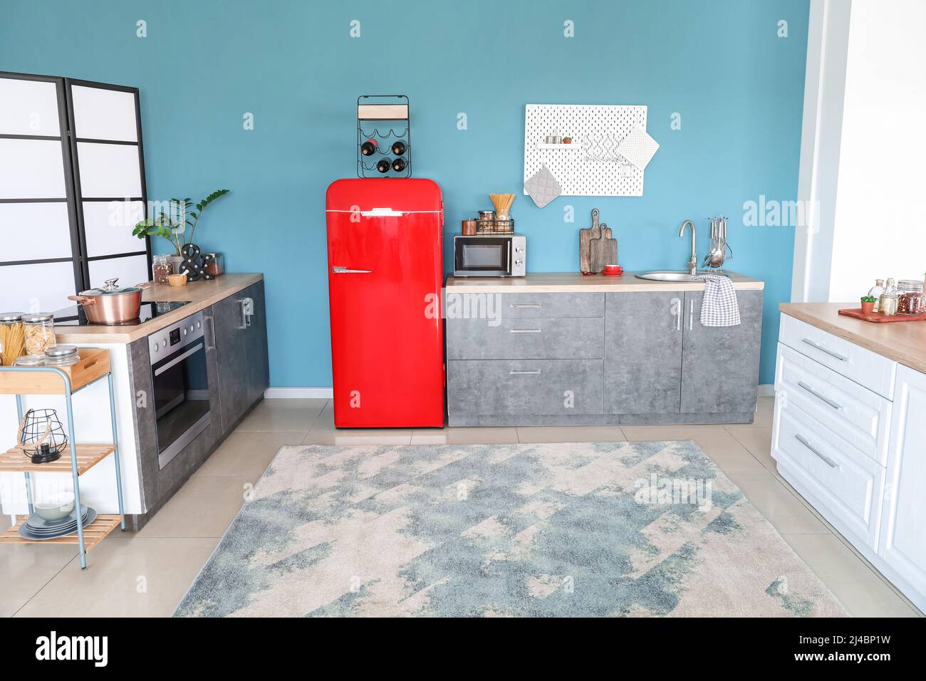 Interior of stylish kitchen with red fridge, counters and pegboard ...