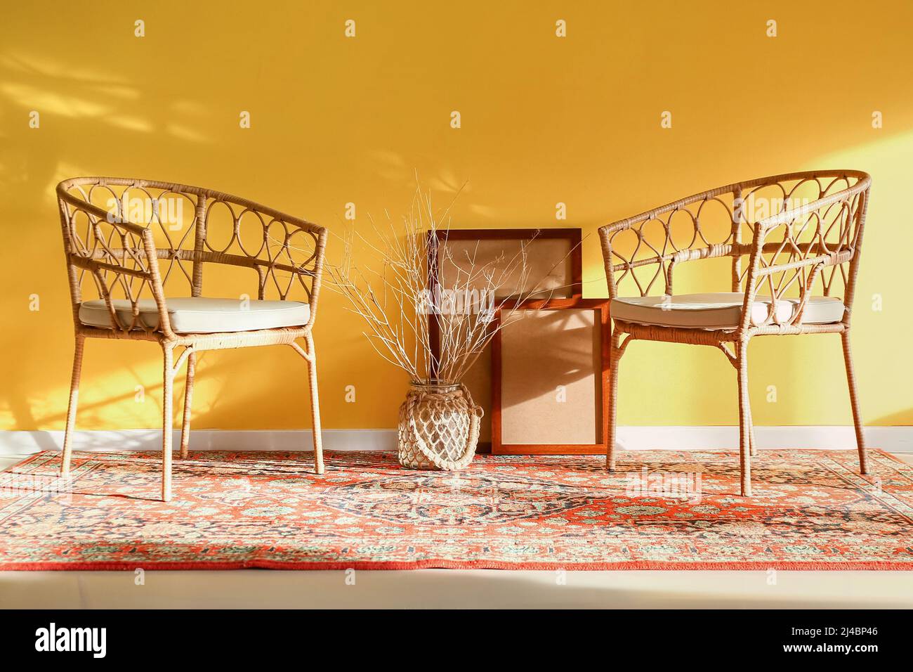 Armchairs, vase with tree branches, frames and vintage carpet near ...