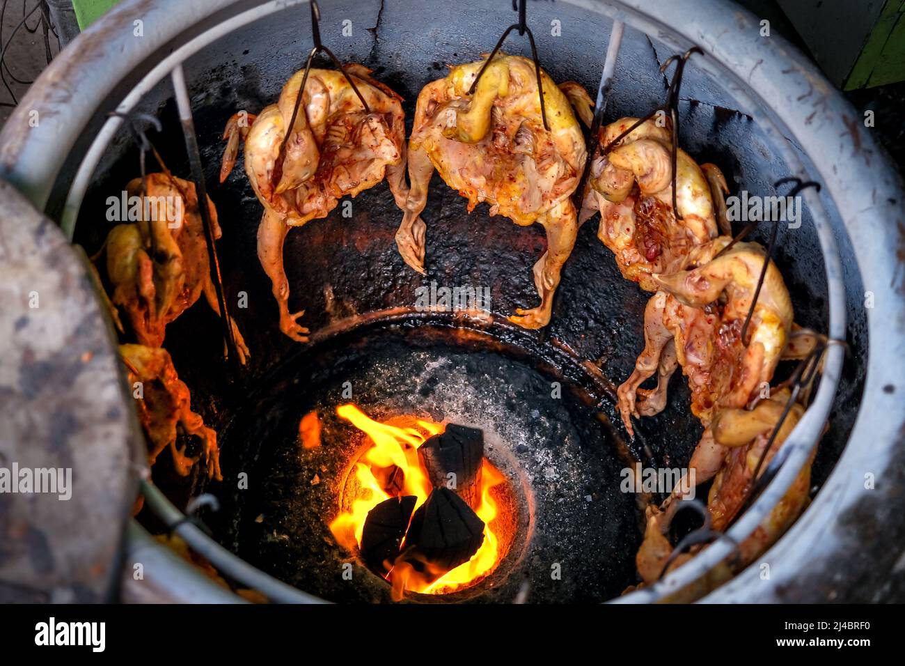 Grilled chicken is hung in a big ceramic pot. Street food in Ho Chi ...