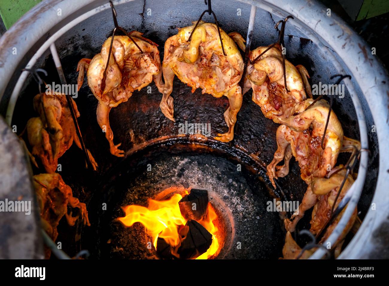 Grilled chicken is hung in a big ceramic pot. Street food in Ho Chi ...