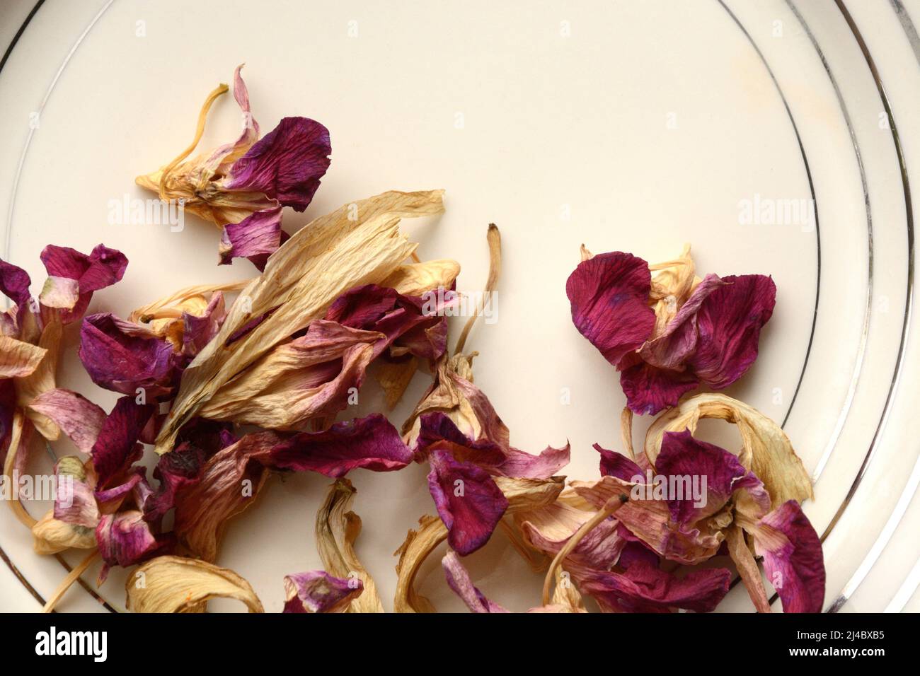 Dried red rose petals and leaves on plate Stock Photo - Alamy