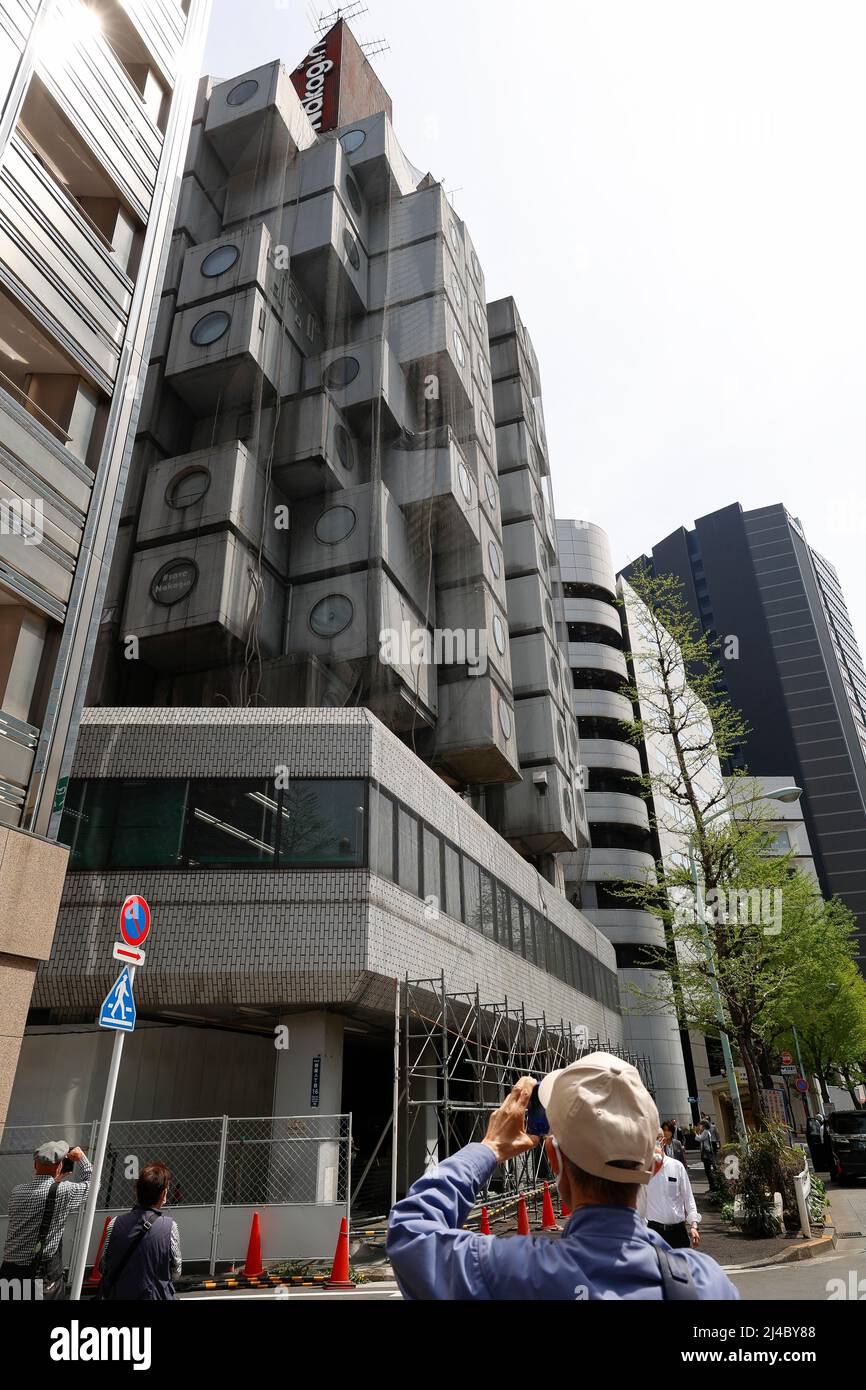 Tokyo, Japan. 13th Apr, 2022. People take photos of the Nakagin Capsule Tower under demolition ...
