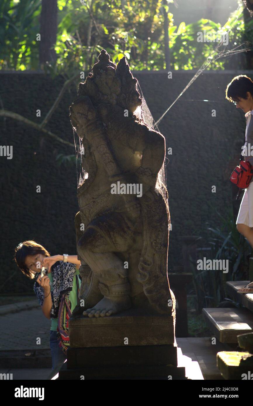 A woman tourist photographing a dvarapala (door guardian) statue at ...