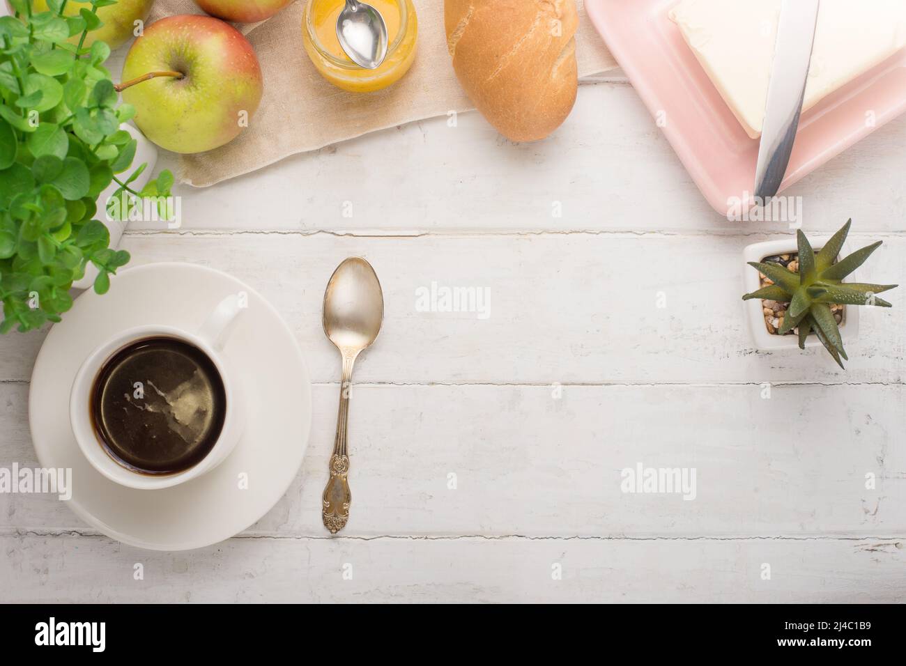 Morning cup of coffee, alarm clock, apples, butter and baguette, in a ...