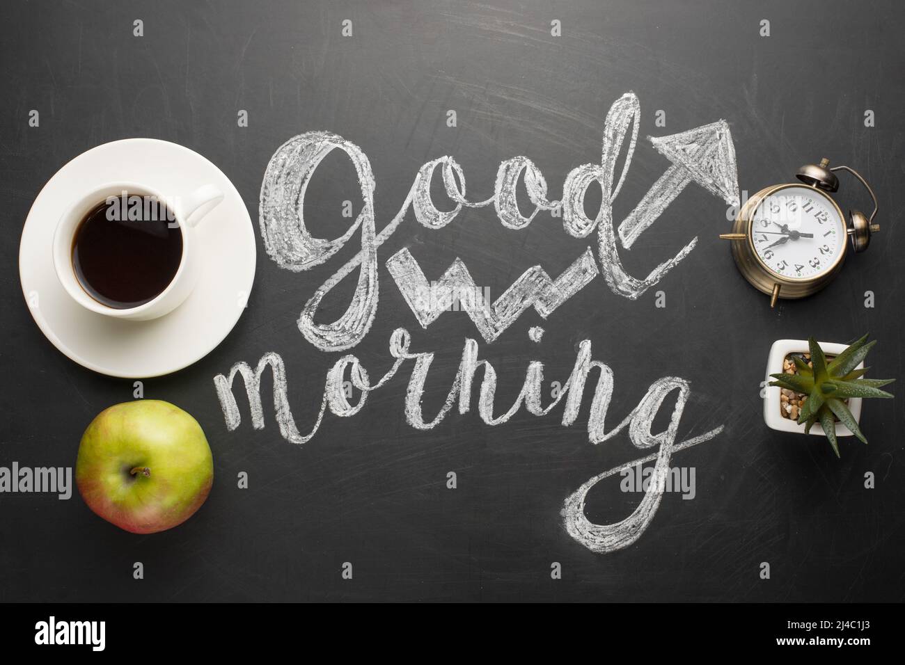 A white cup of coffee with an alarm clock and an apple and a good ...