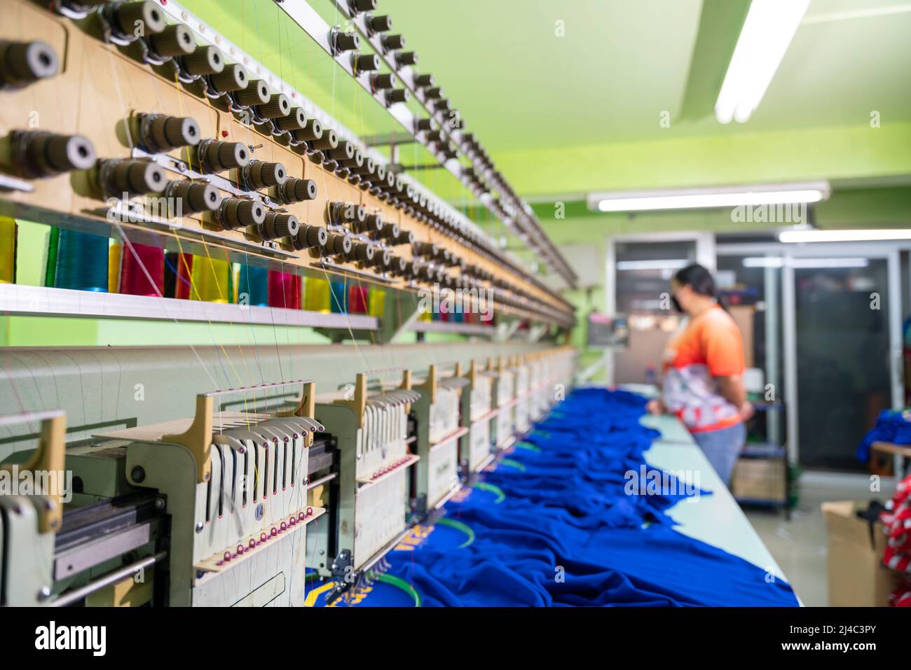 A worker stands in control of a sewing machine. Embroidery area in ...