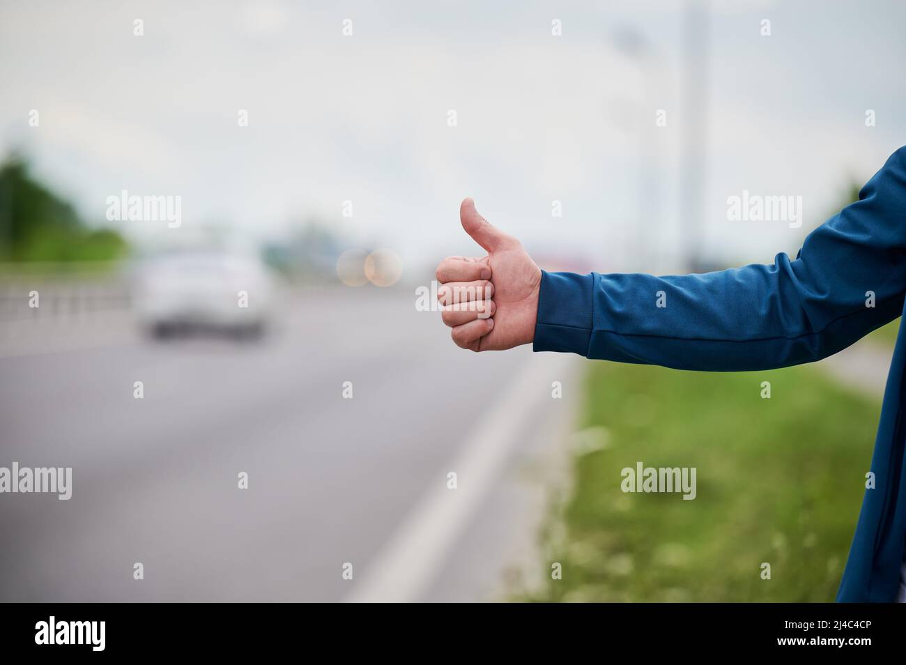 Close up of man's hand hitchhiking by roadside. Male hand showing ...