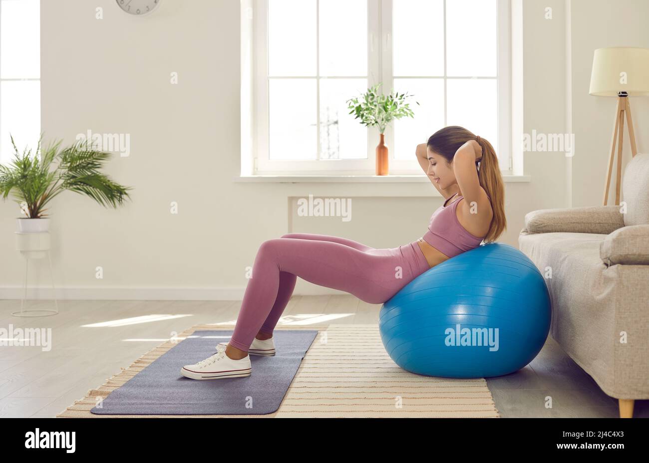 Active slender young woman at home trains muscles of her abs using ...