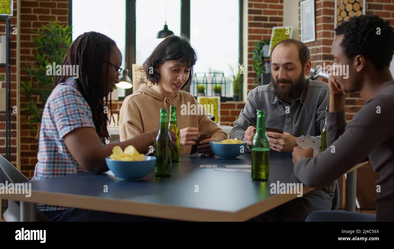 Diverse group of friends playing cards at fun gathering, enjoying ...