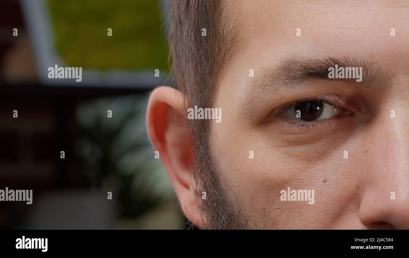 Macro shot of man showing one eye and half face on camera, showing ...