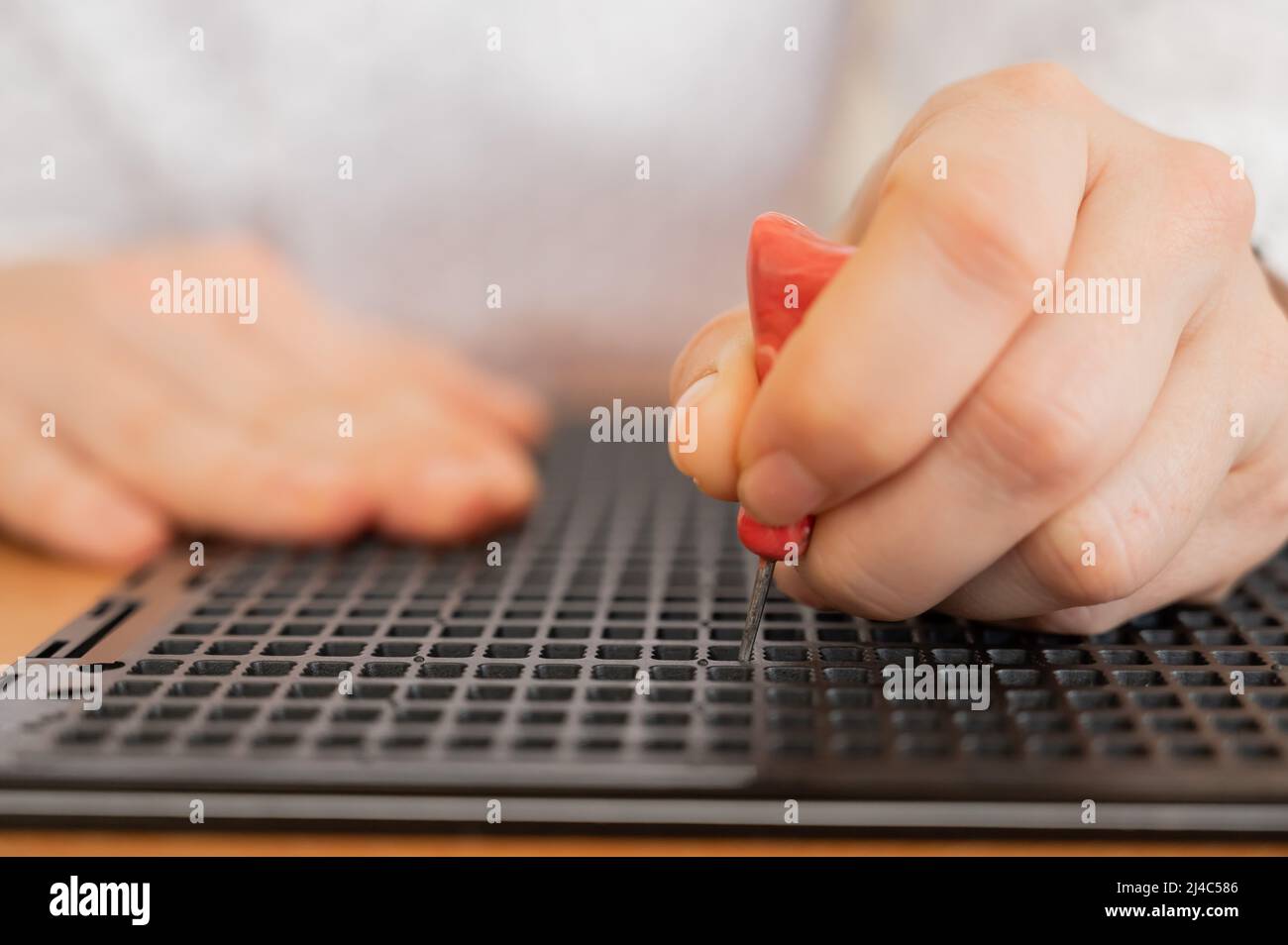 A woman uses a special stencil and stylus to write a letter in braille ...