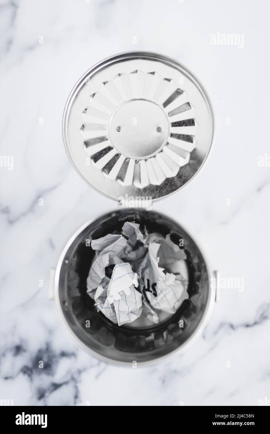 garbage bin with scrunched paper inside of it, concept of writer's ...