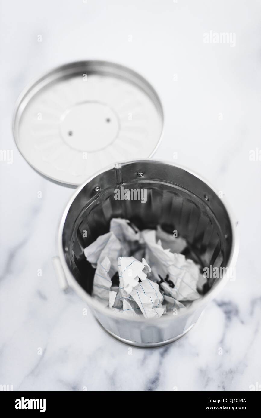garbage bin with scrunched paper inside of it, concept of writer's ...