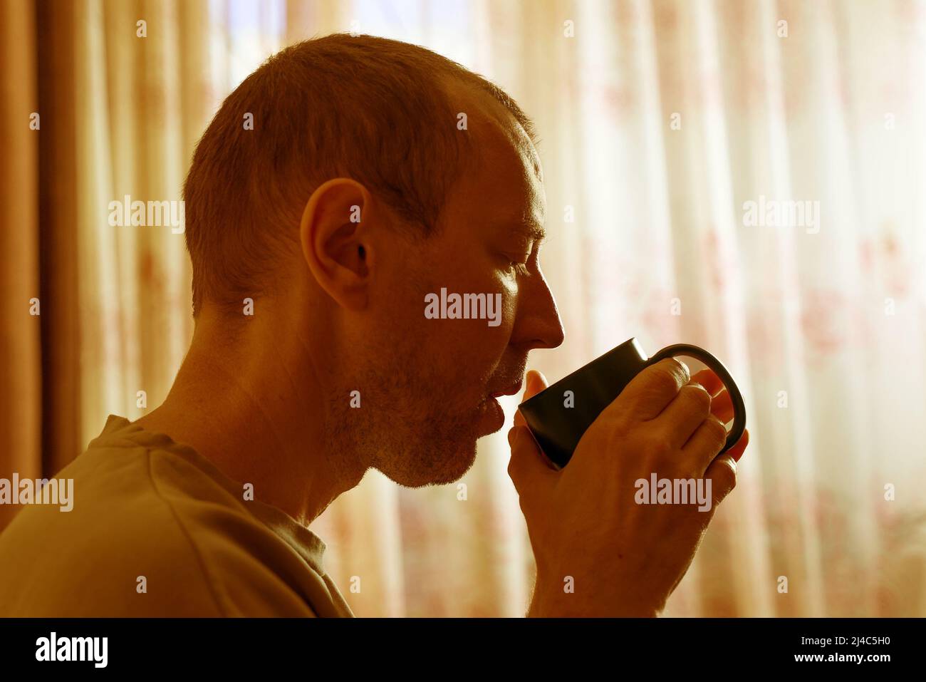 Portrait of a man drinking coffee from a black cup. A European drinks ...