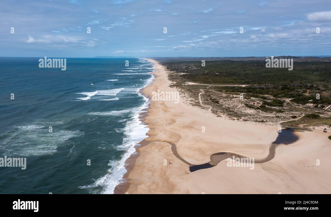 High angle drone view of a wide endless golden sand beach with a river ...