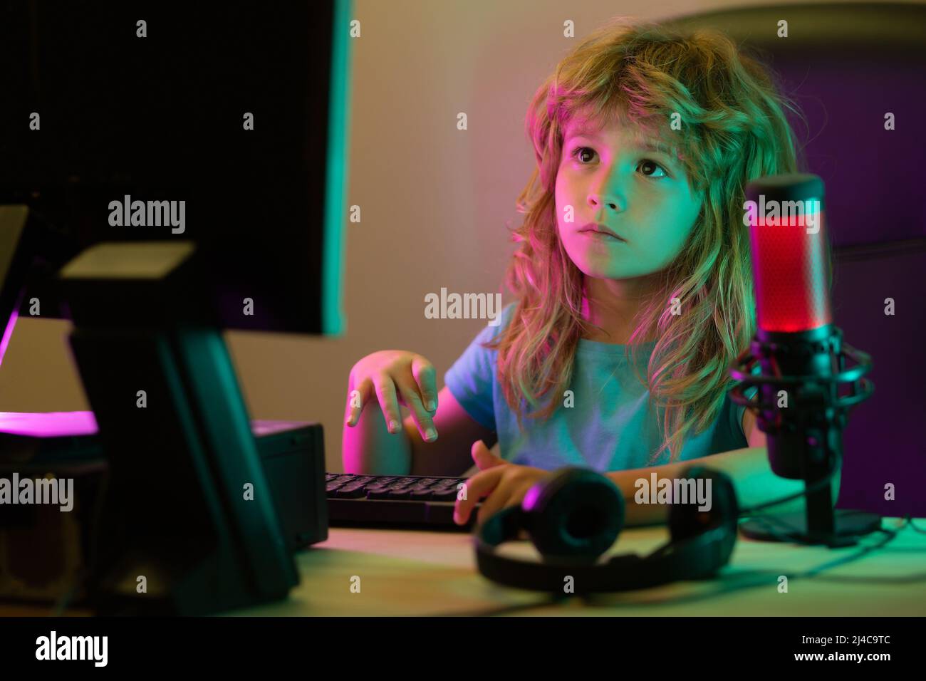 Kid using pc at night. A pretty child learns a lesson using a desktop ...