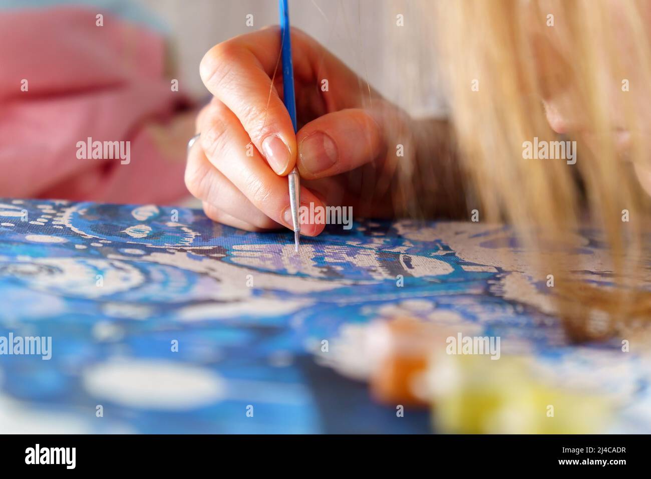Close up of a young woman artist hand painting a picture by numbers ...