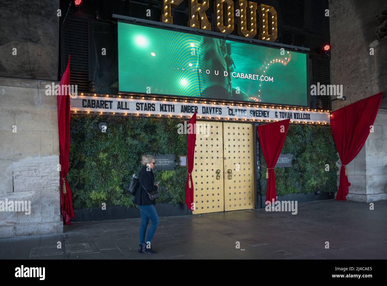 A lone woman passes Proud Embankment, a cabaret club situated under ...