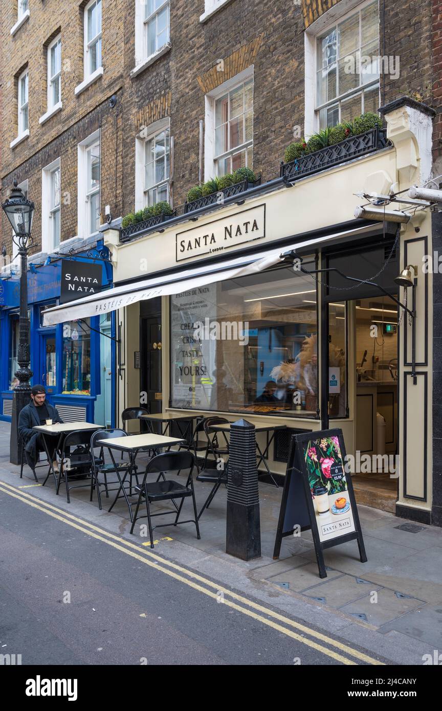 A lone young man seated at pavement table outside Santa Nata, a shop ...