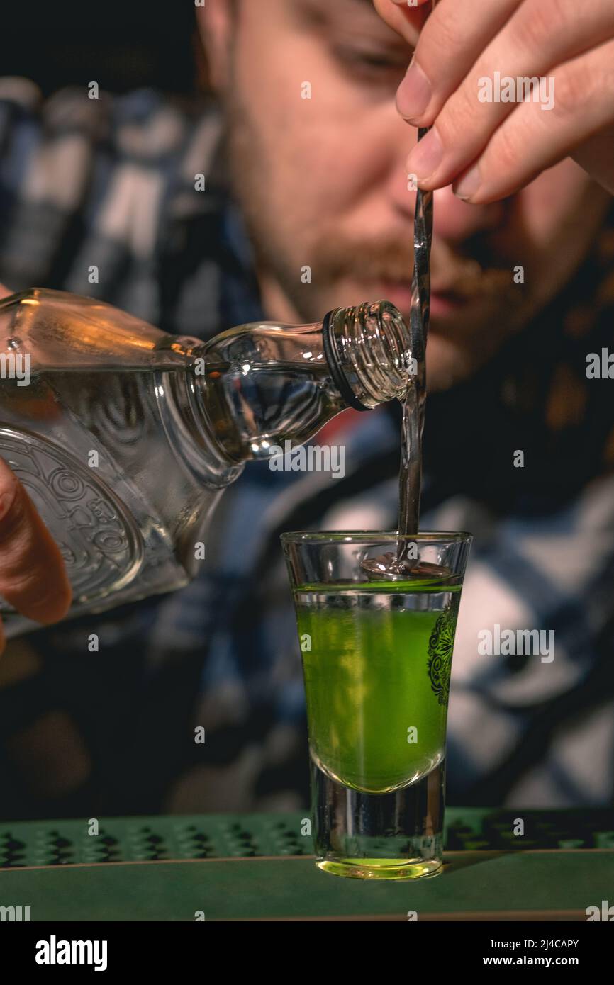 Skilled bartender preparing layered drink Green Mexican on bar counter ...