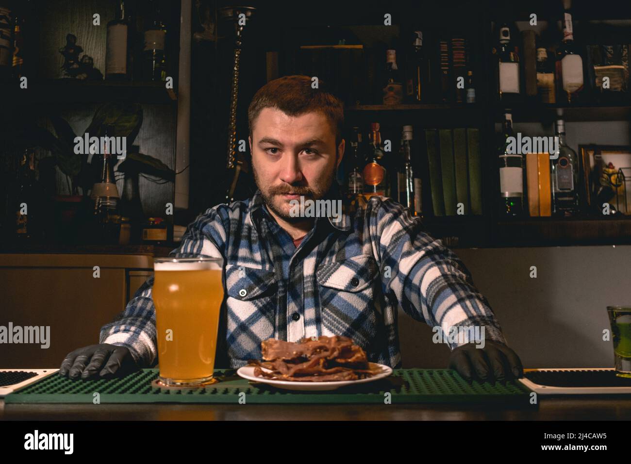 Bartender standing behind bar counter in pub with glass of beer and ...
