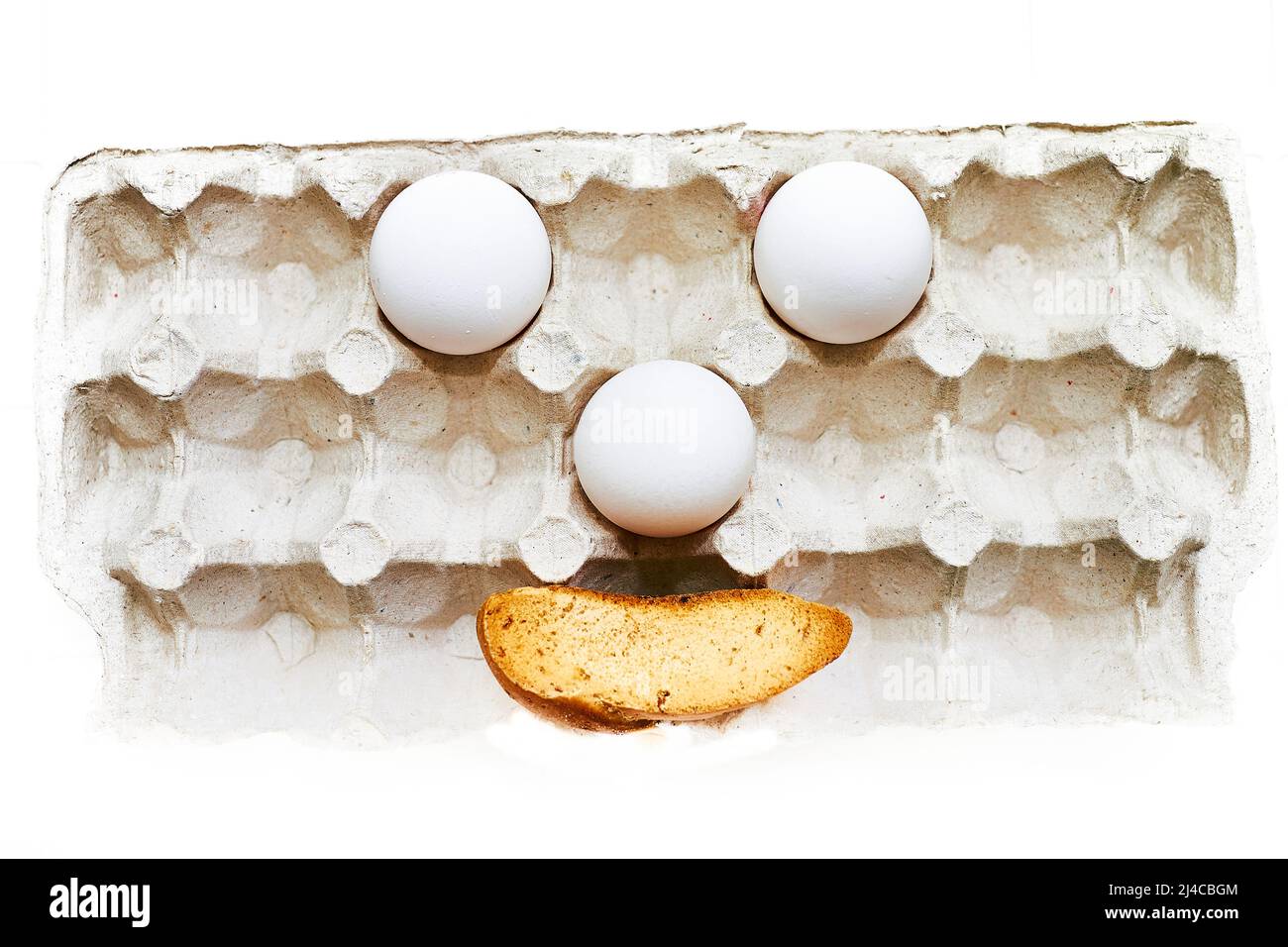 Three white eggs and smile cracker in a cardboard tray on a white ...
