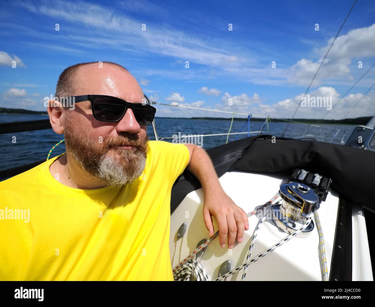 one smiling bearded adult man sailing on a sailboat during his yacht ...