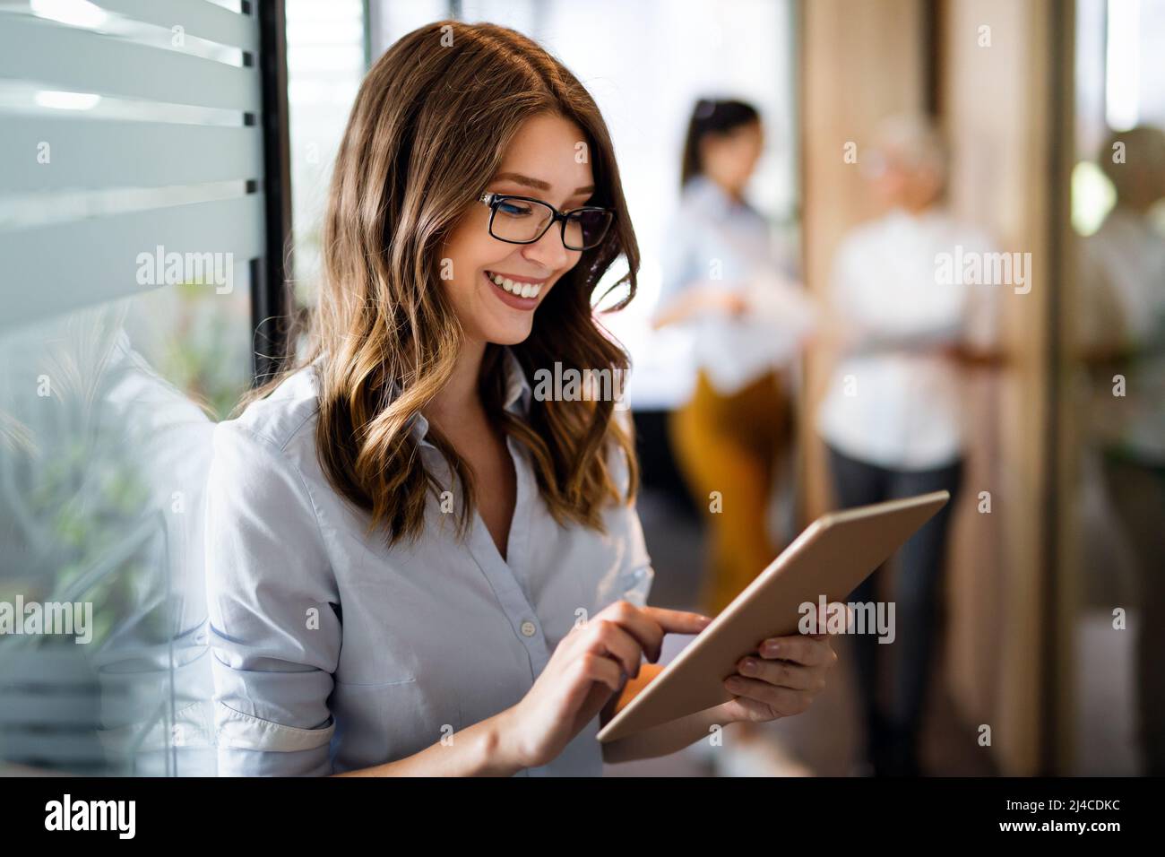 Attractive young businesswoman using a digital tablet while standing in ...